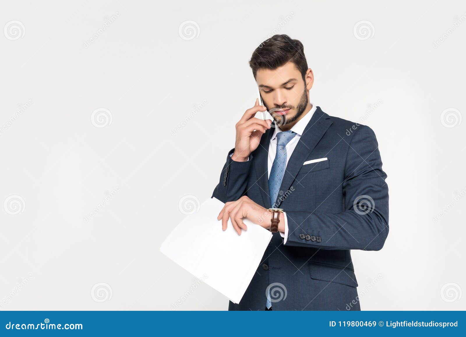 Young Businessman Holding Papers and Talking on Smartphone while ... Young Businessman Holding Papers and Talking on Smartphone while ...
