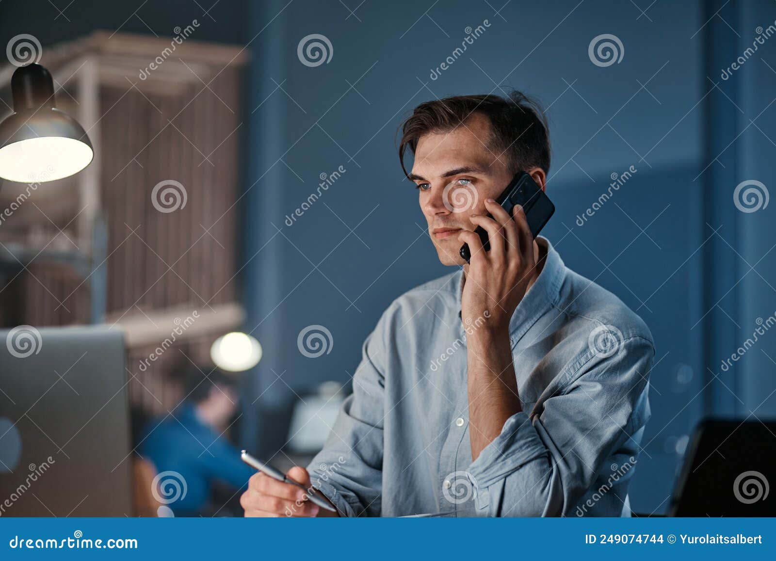 Young Businessman Making a Call from the Office at Night. Stock Photo ...