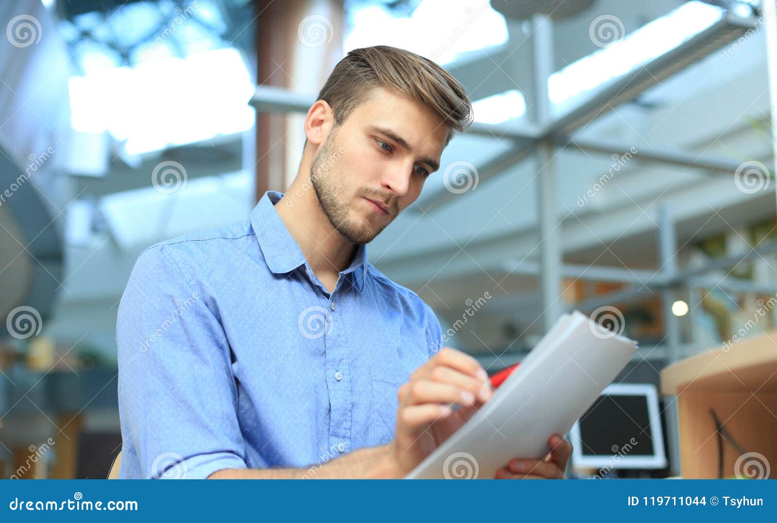 Young Businessman Reading Paperwork at Desk in Office. Stock Photo ...