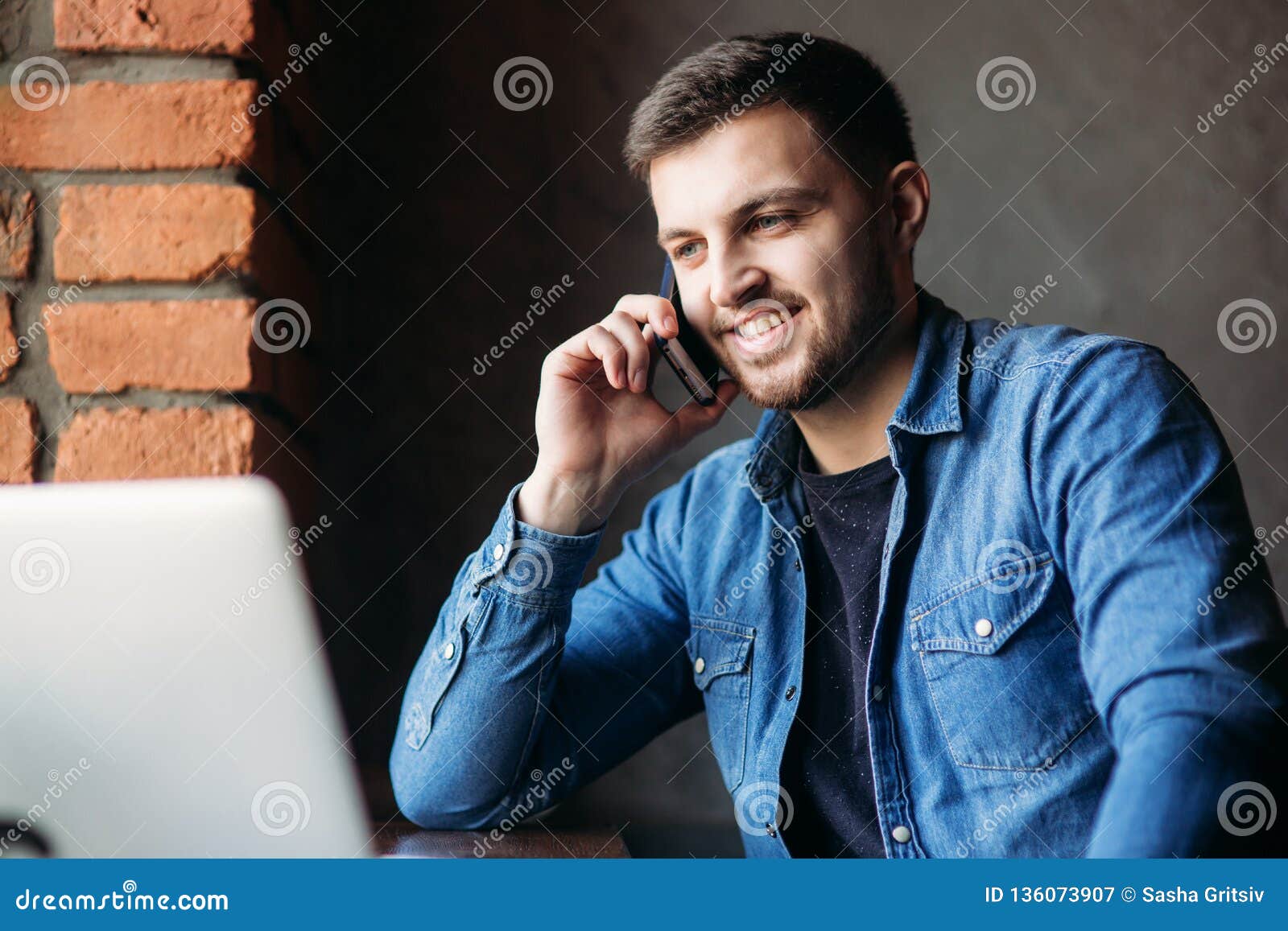 Young Businessman Taking a Call in Cafe while he Use a Laptop Stock ...
