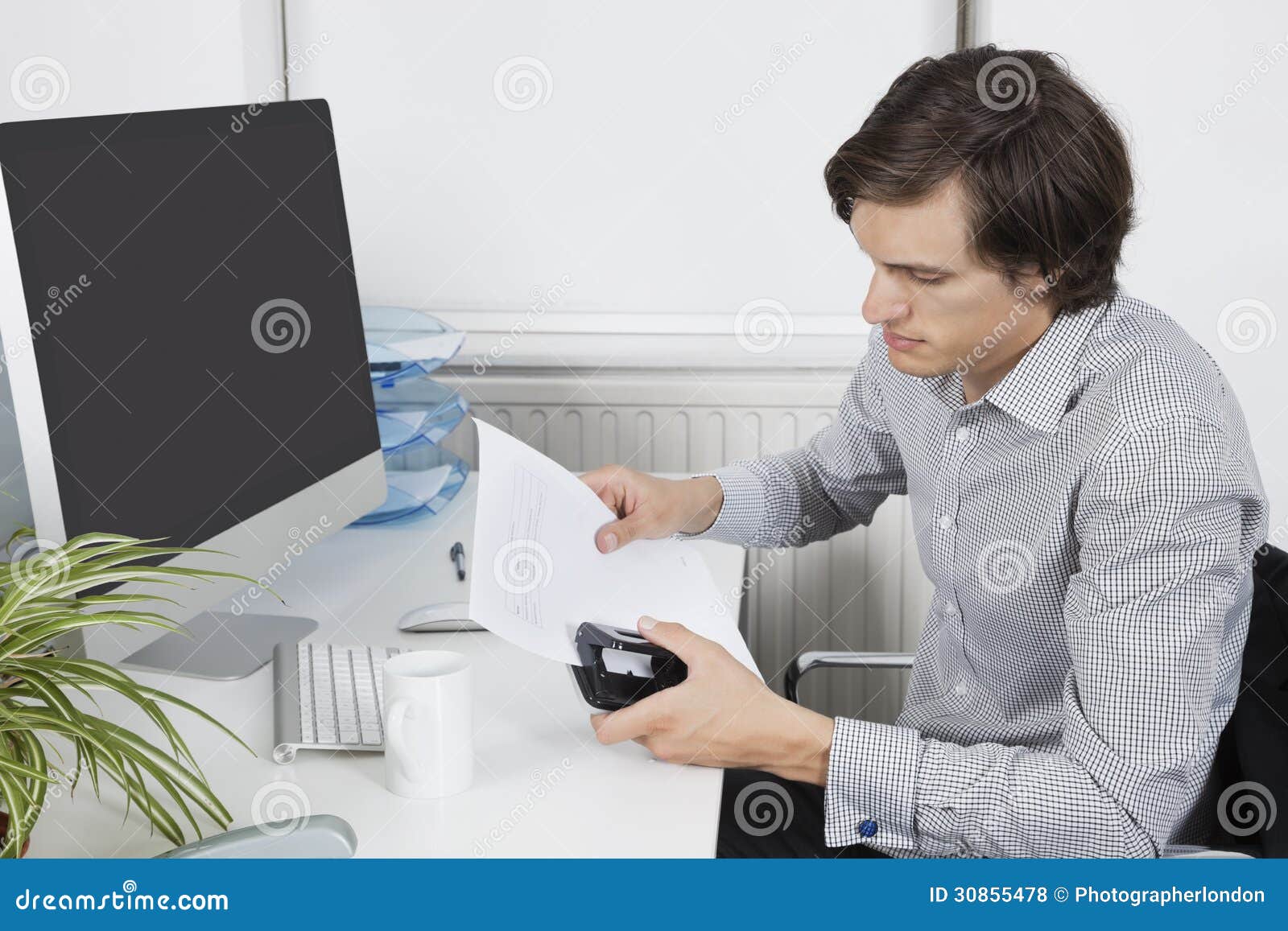 Young Businessman Using Hole Puncher at Desk Stock Photo - Image of ...