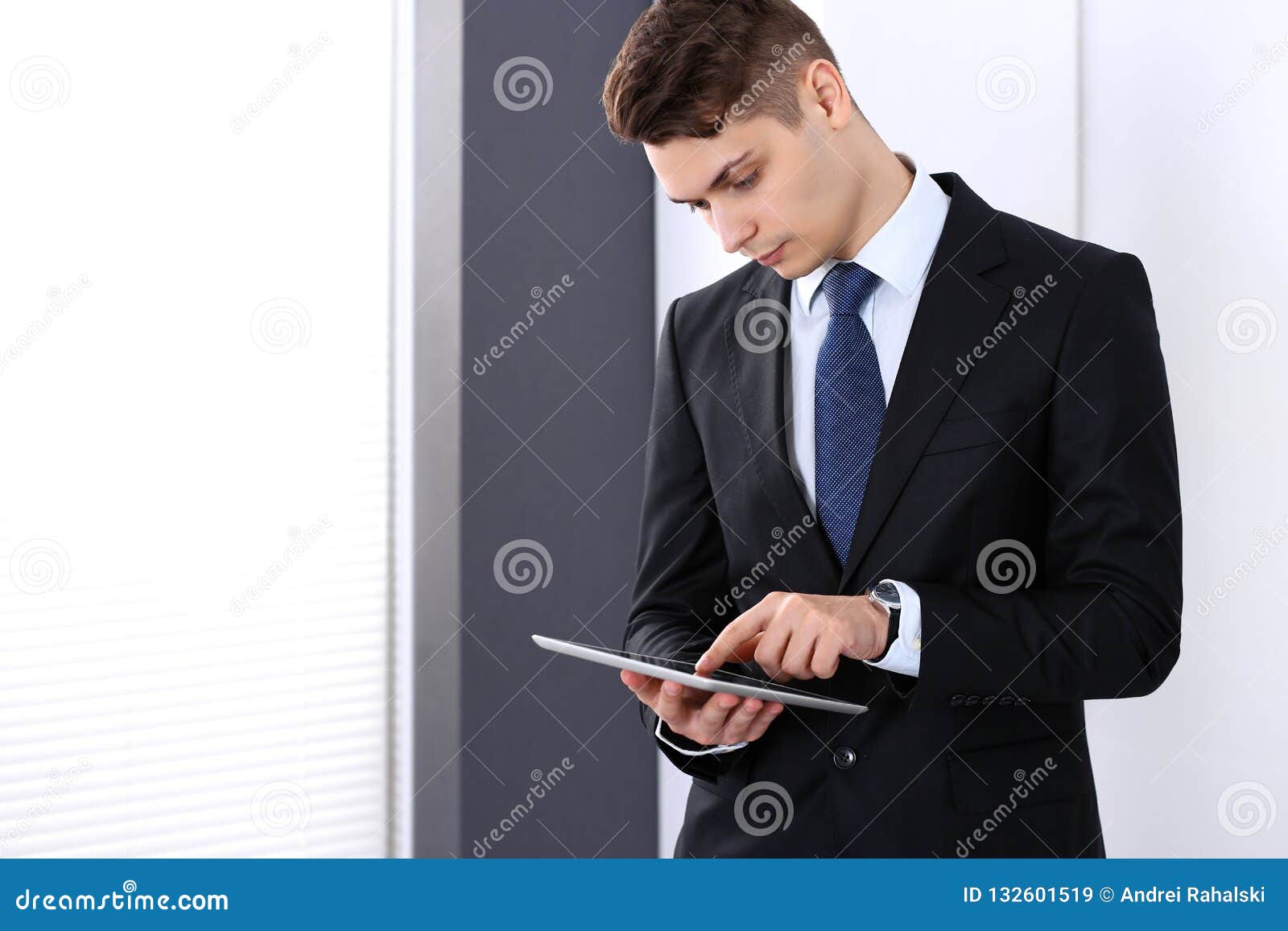 Young Businessman Using Tablet Computer while Standing Straight in ...