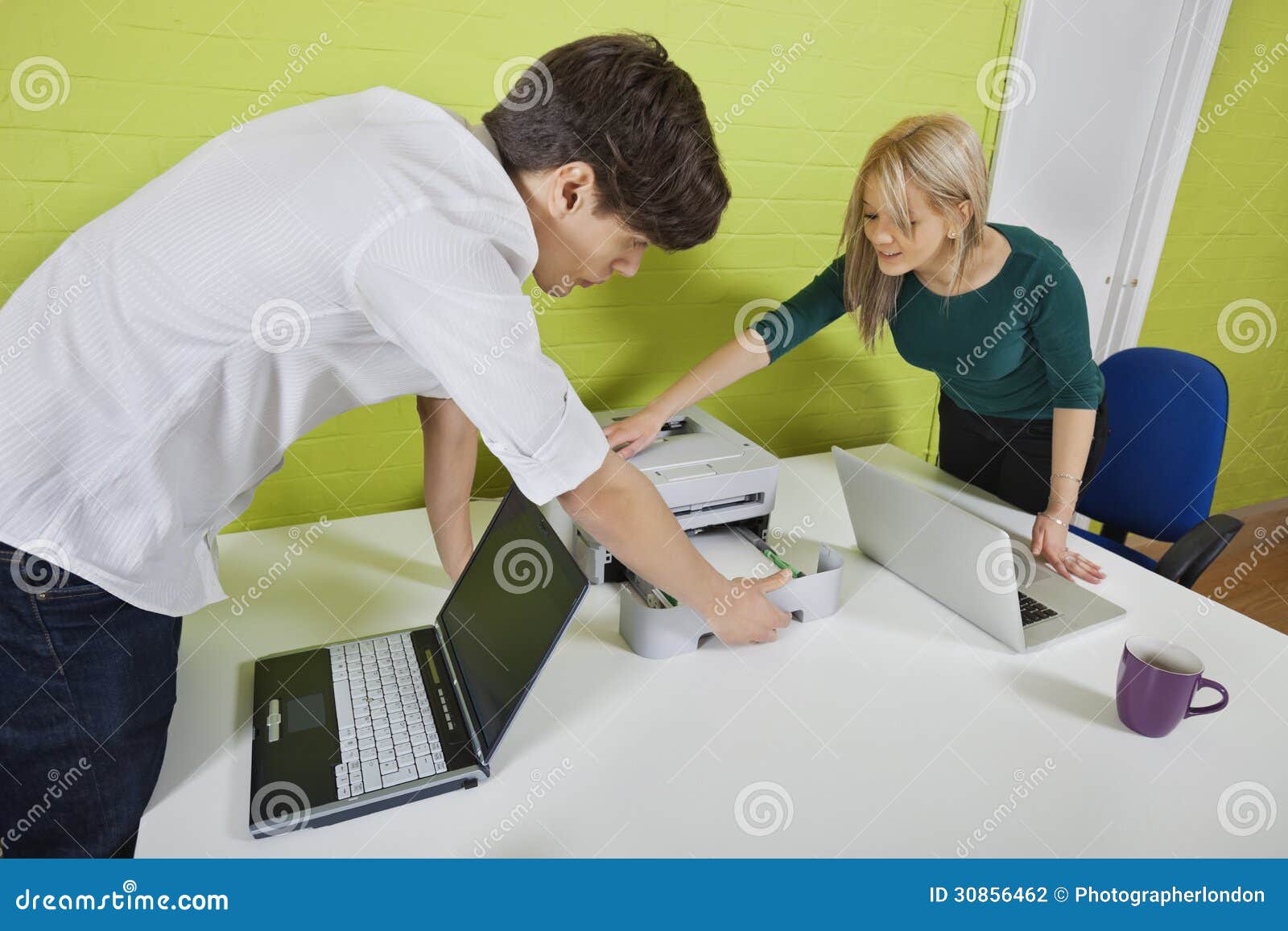 Young Businesspeople Setting Up Printer with Laptops at Desk Stock ... Young Businesspeople Setting Up Printer with Laptops at Desk Stock ...