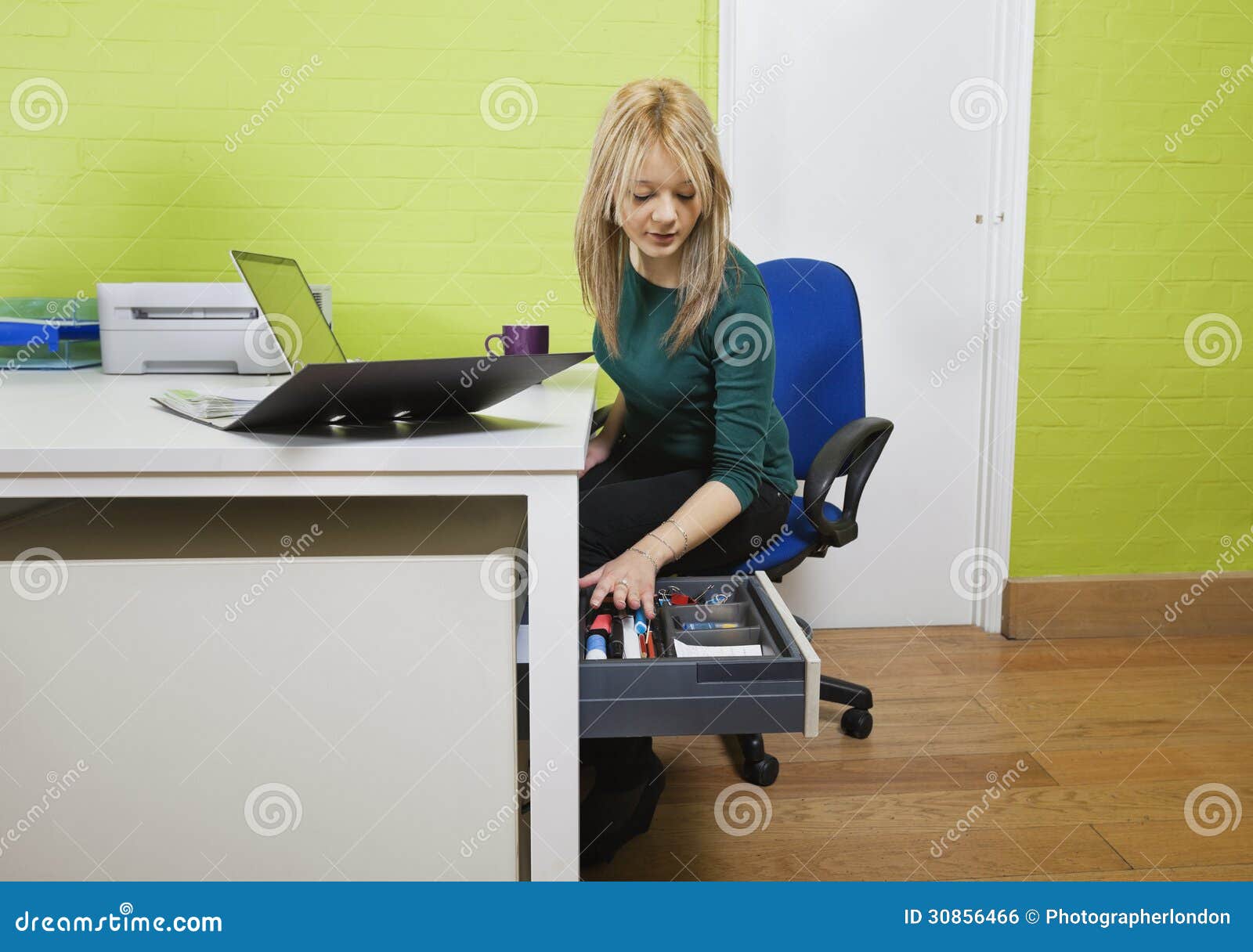 Young Businesswoman Searching Something in Drawer with Laptop and File ...