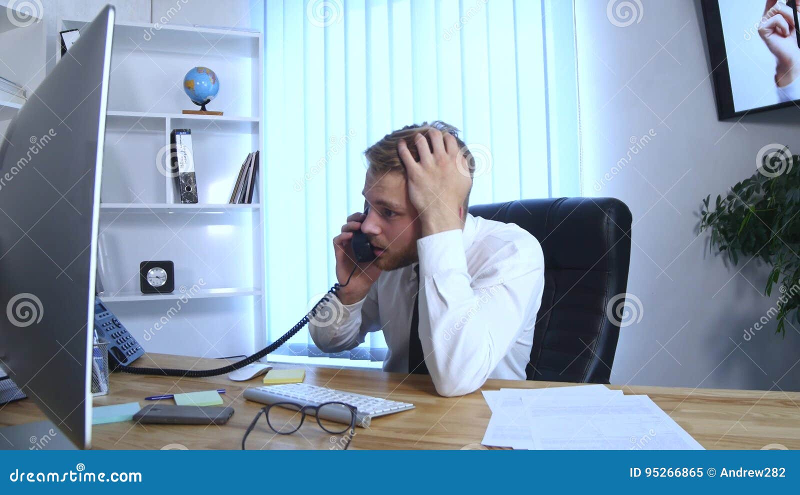 Young Busy Business Man Talking on Mobile Phone and Office Telephone ...