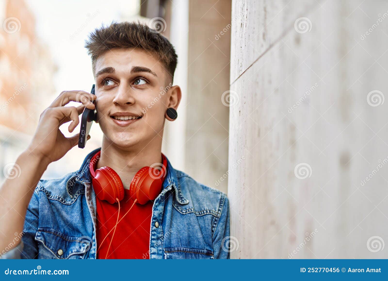 Young Caucasian Guy Smiling Using Smartphone Leaning on the Wall Stock ...