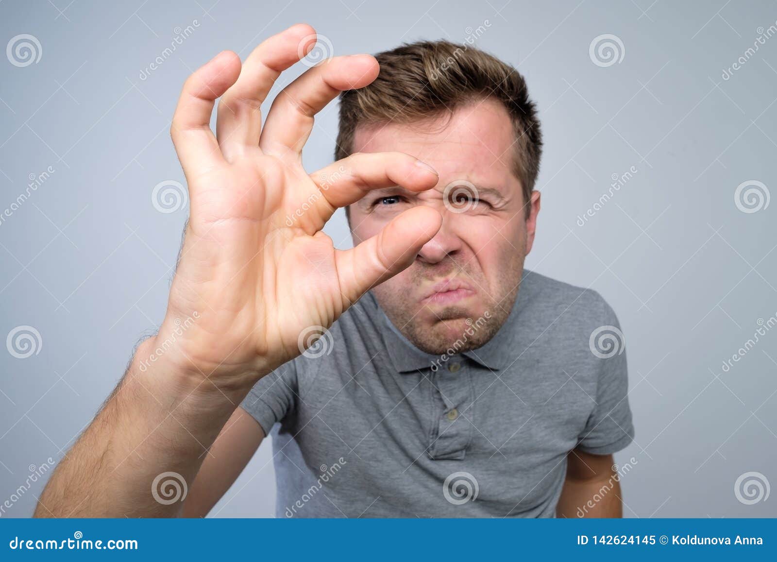 Young Caucasian Man Gesturing with Hand Showing Small Size Sign with ... Young Caucasian Man Gesturing with Hand Showing Small Size Sign with ...