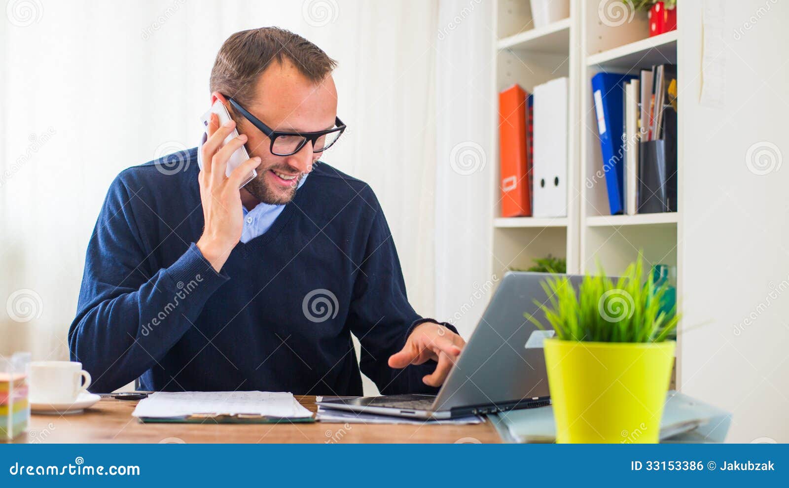 A Young Caucasian Man Working on a Desk with a Laptop and Mobile Phone ...