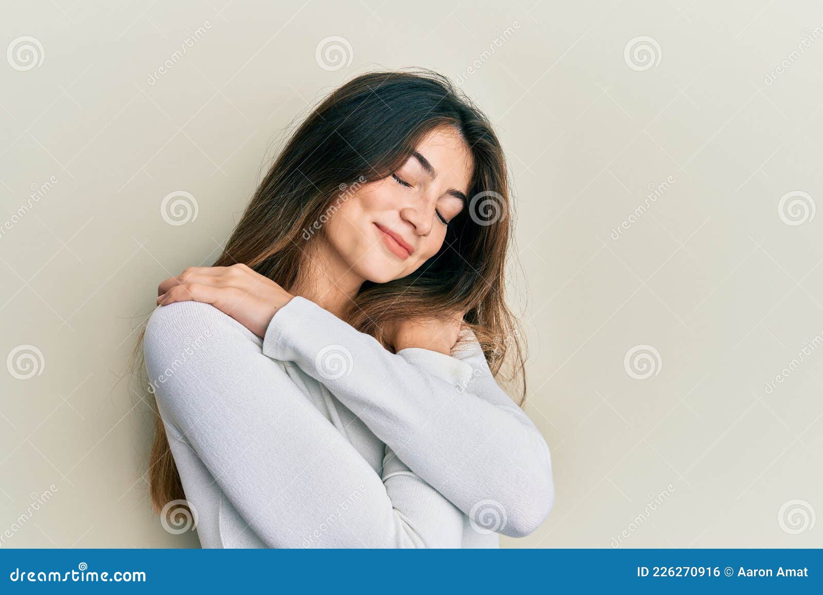 Young Caucasian Woman Wearing Casual White T Shirt Hugging Oneself