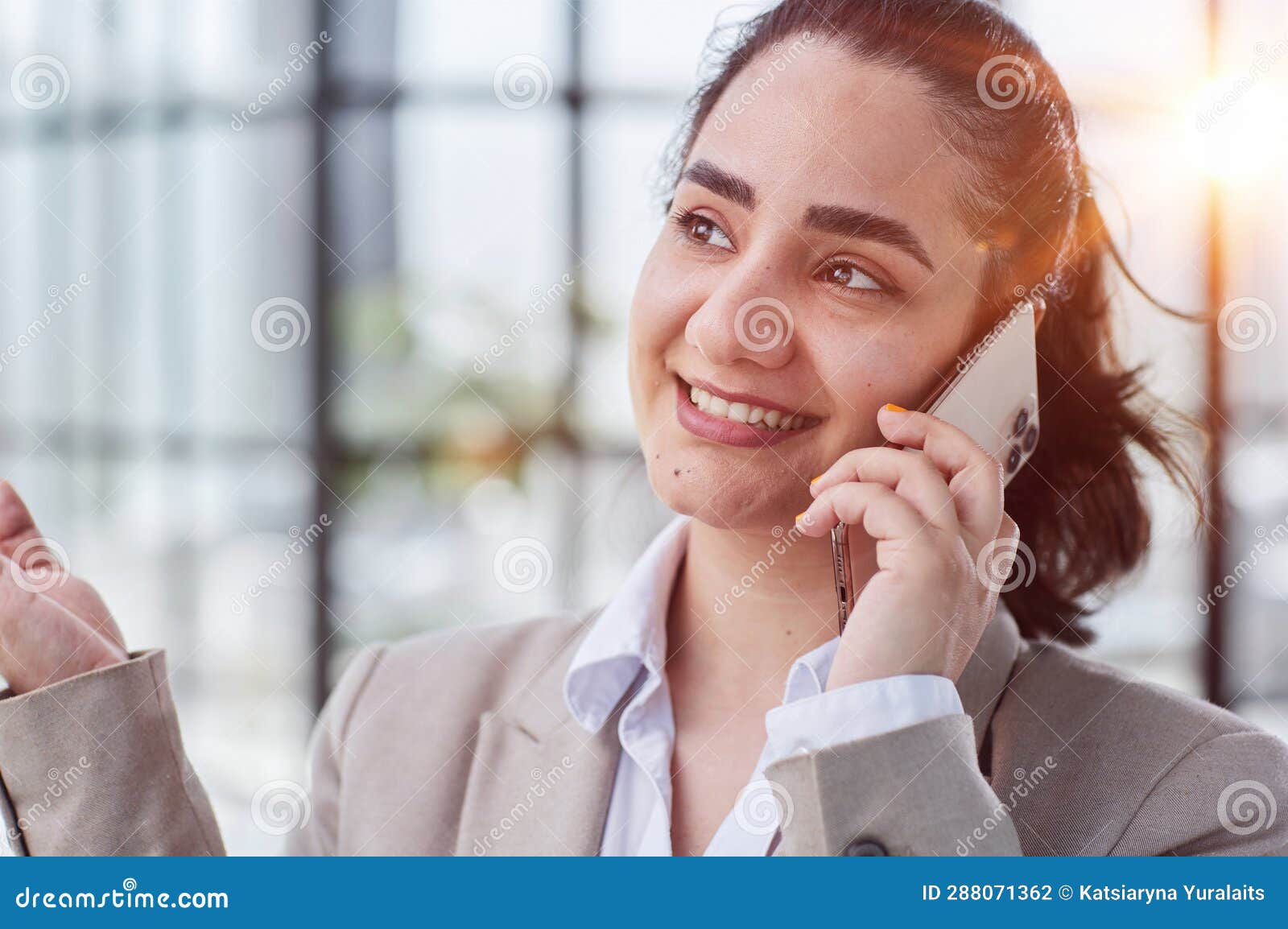 Attractive Woman Talking On Mobile Phone While Relaxing In Office Stock