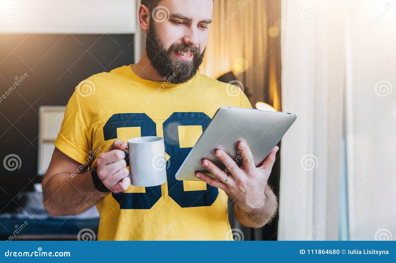 Cheerful Bearded Man Stands and Using Tablet Computer. Guy Laughs ...