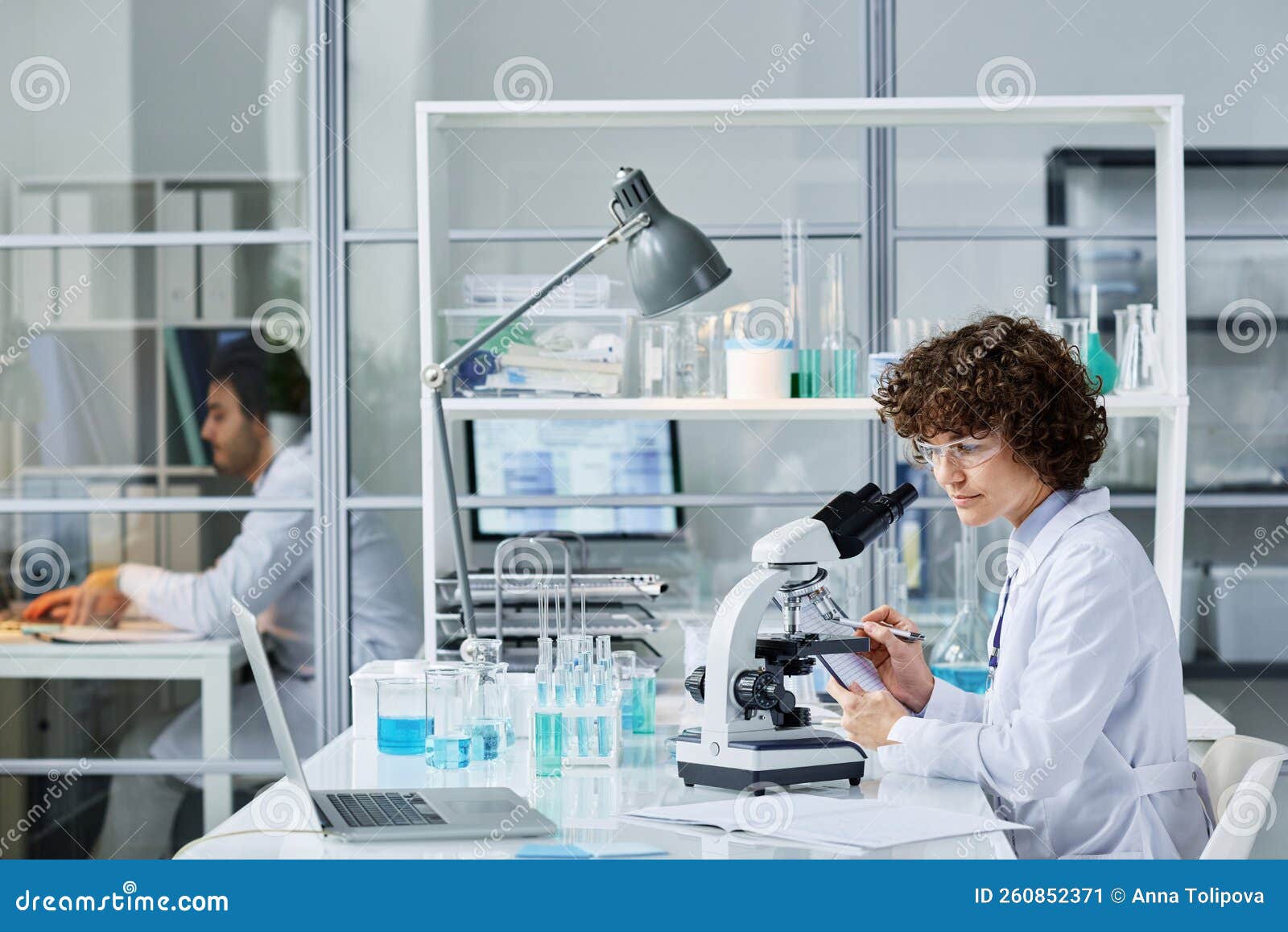 Young Chemist or Microbiologist in Labcoat and Protective Eyeglasses ...
