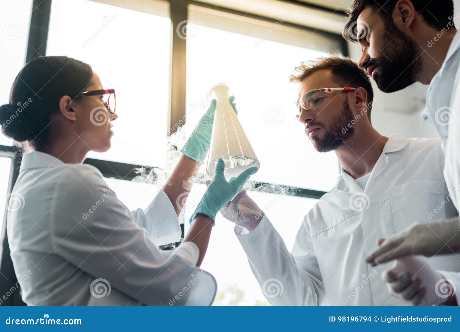 Young Chemists in Eyeglasses and White Coats Making Experiment in ...