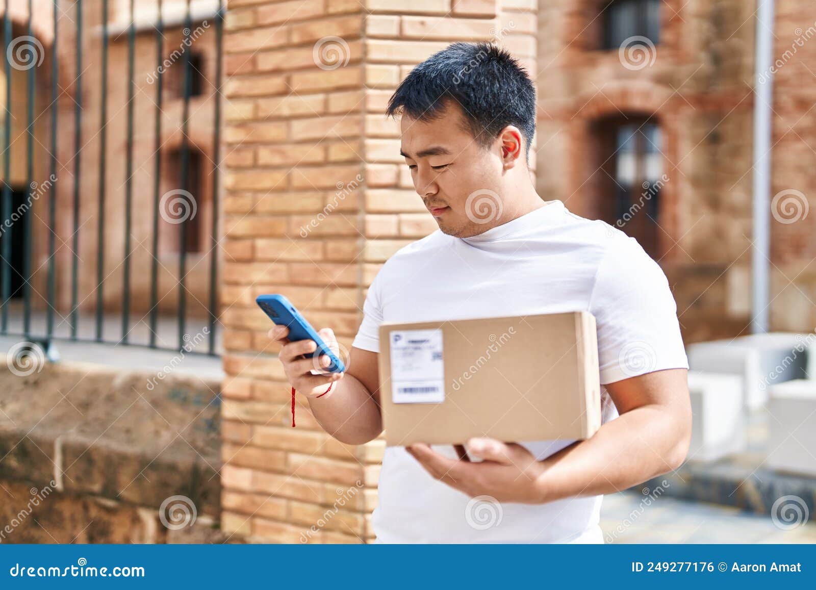 Young Chinese Man Courier Using Smartphone Holding Package at Street ...