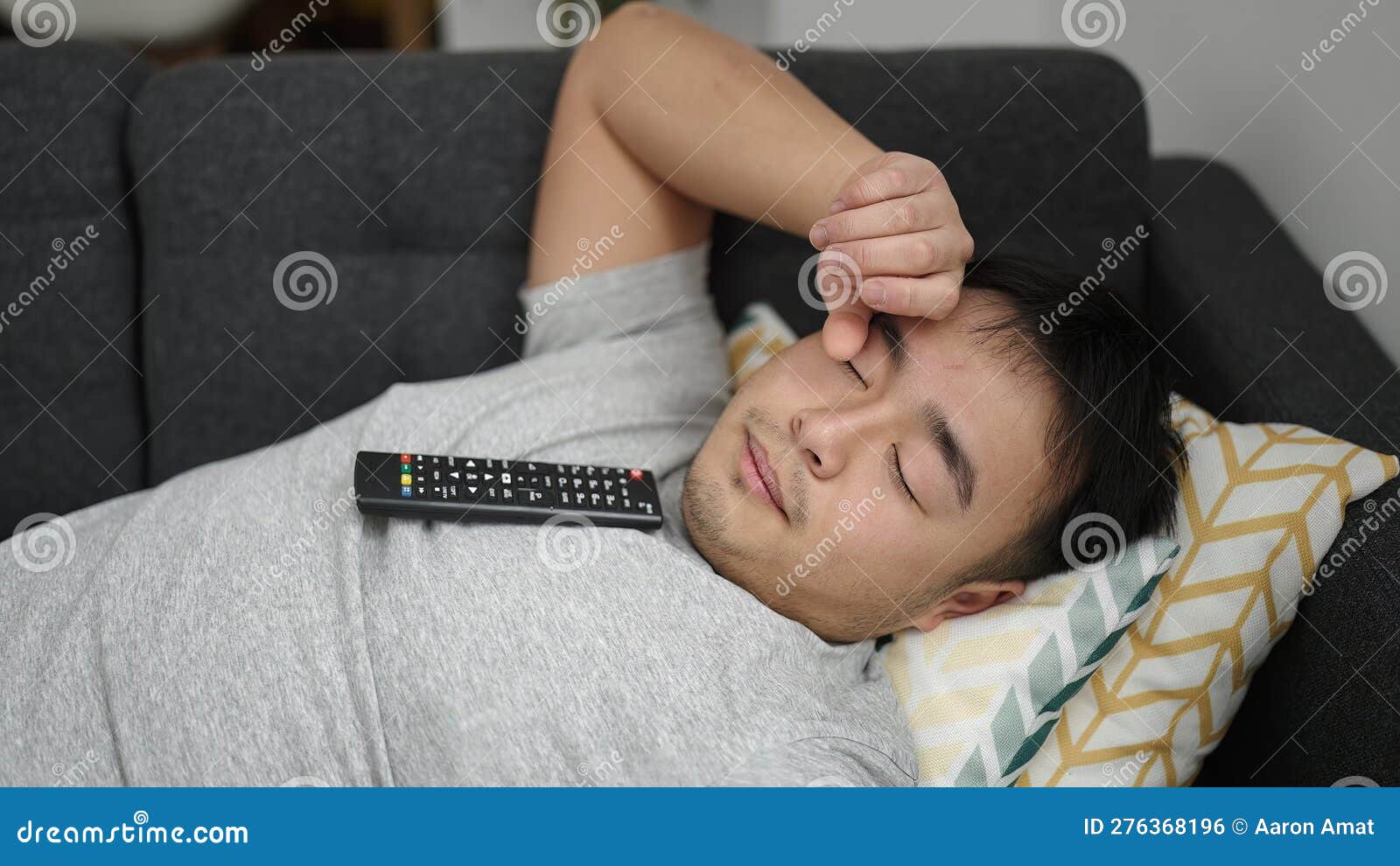 Young Chinese Man Holding Tv Remote Control Lying on Sofa Sleeping at ...