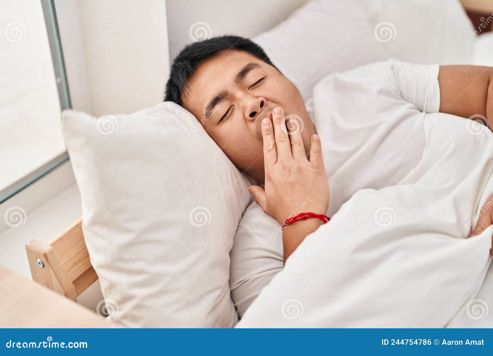 Young Chinese Man Lying on Bed Yawning at Bedroom Stock Photo - Image ...