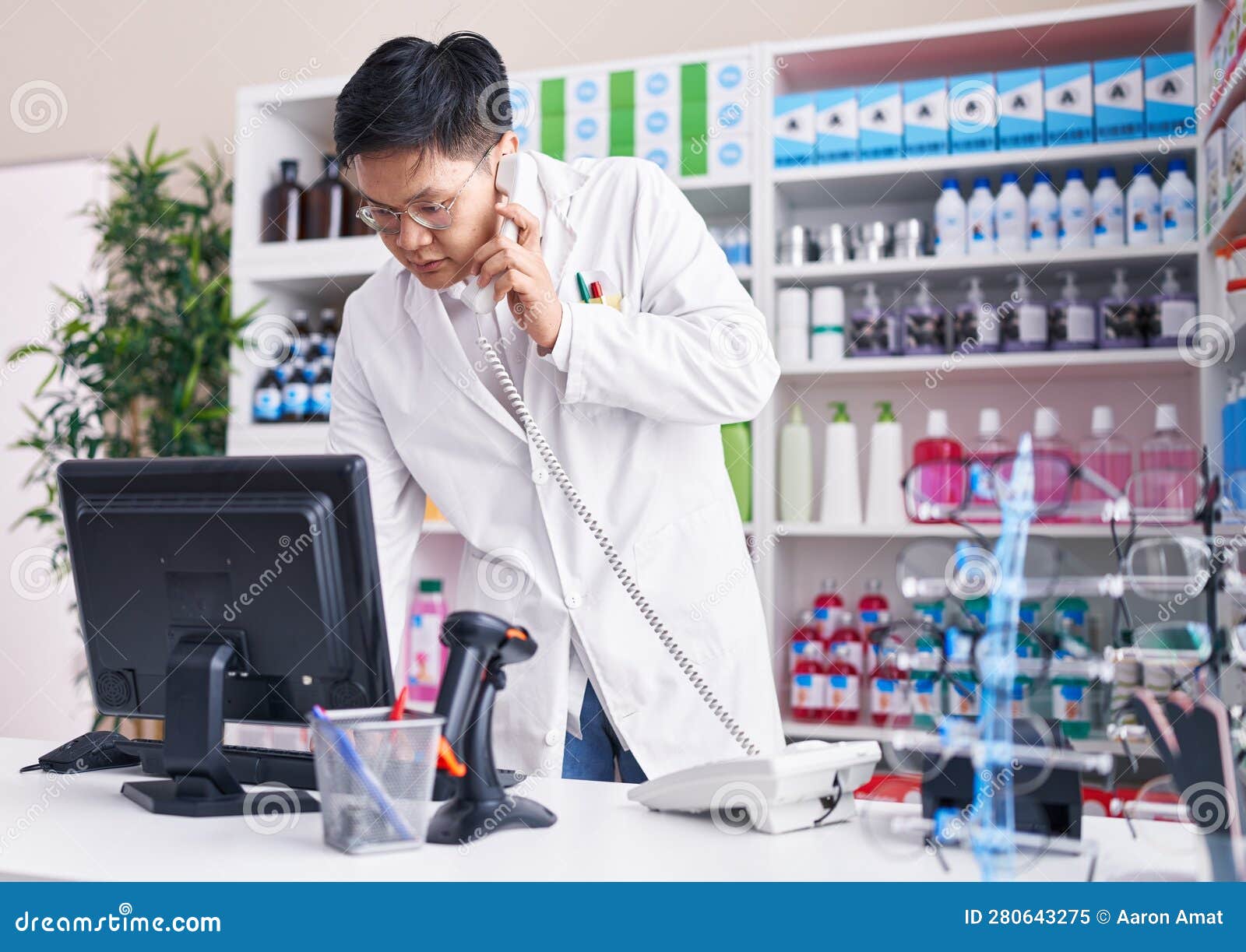 Young Chinese Man Pharmacist Talking on Telephone Using Computer at ...