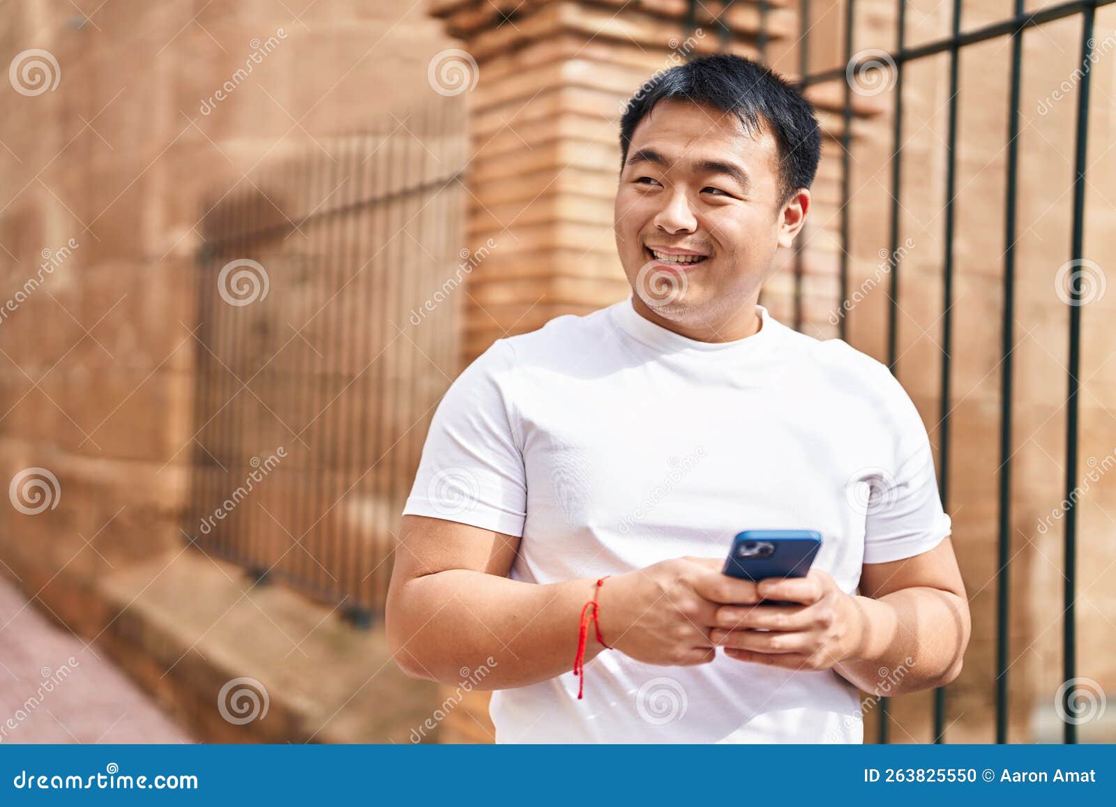 Young Chinese Man Smiling Confident Using Smartphone at Street Stock ...