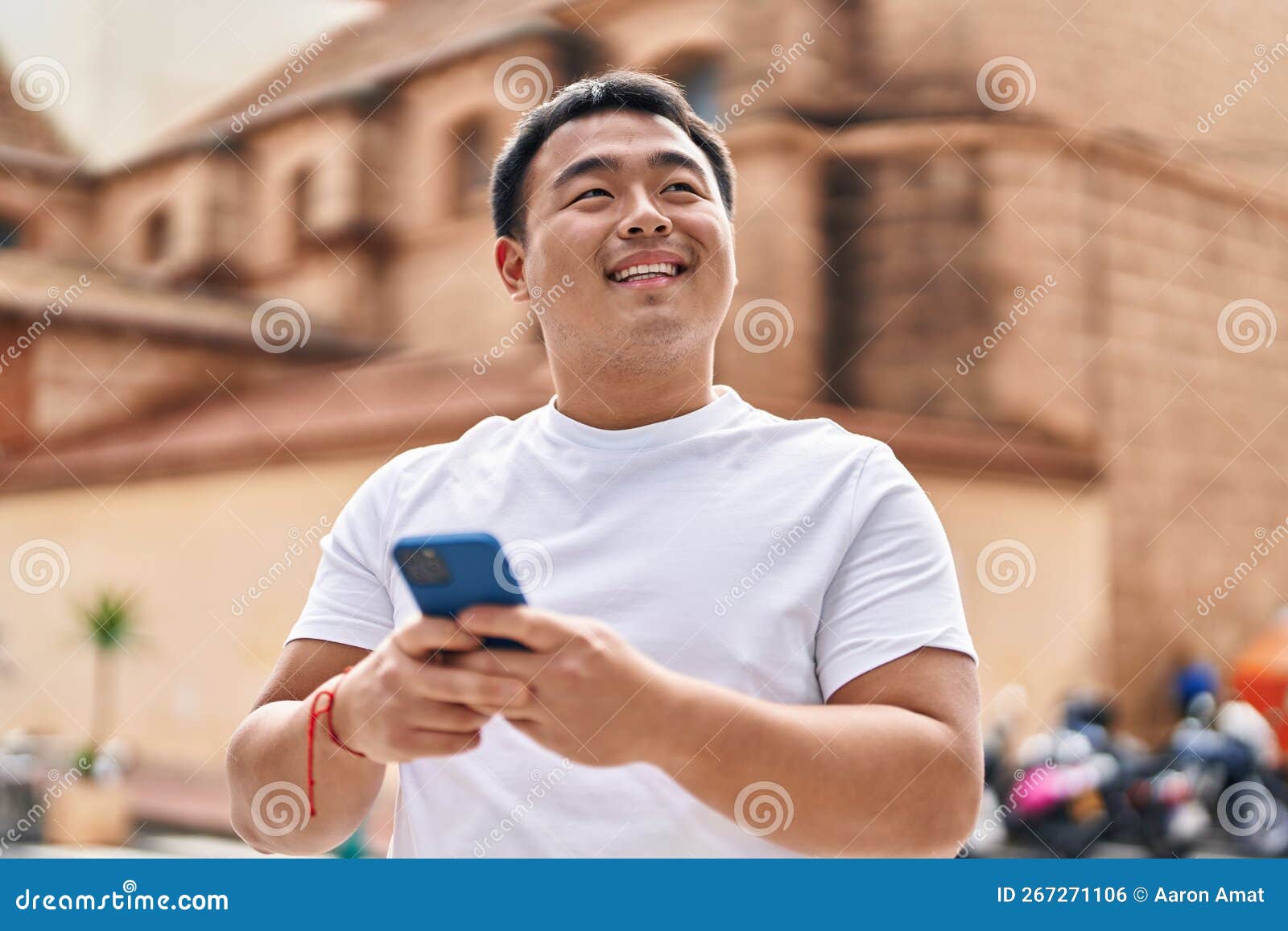 Young Chinese Man Smiling Confident Using Smartphone at Street Stock ...