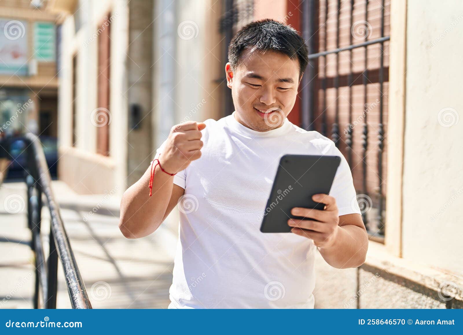 Young Chinese Man Smiling Confident Using Touchpad at Street Stock ...