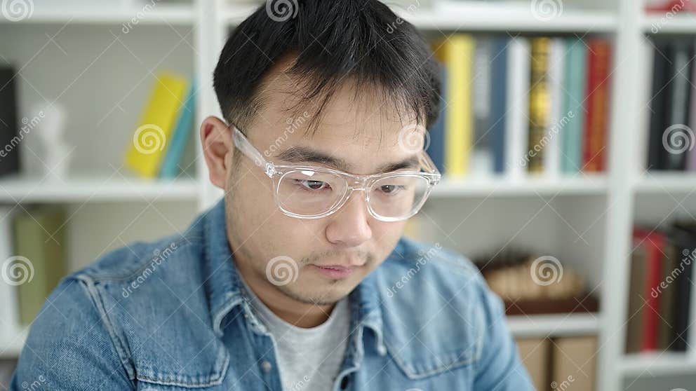 Young Chinese Man Student Sitting on Table with Relaxed Expression at ...