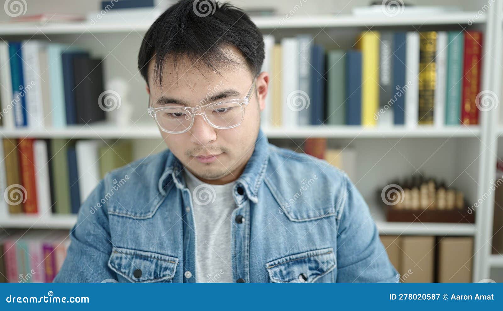 Young Chinese Man Student Sitting on Table with Relaxed Expression at ...