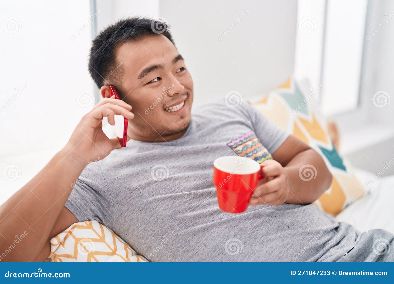 Young Chinese Man Talking on Smartphone Drinking Coffee at Bedroom ...