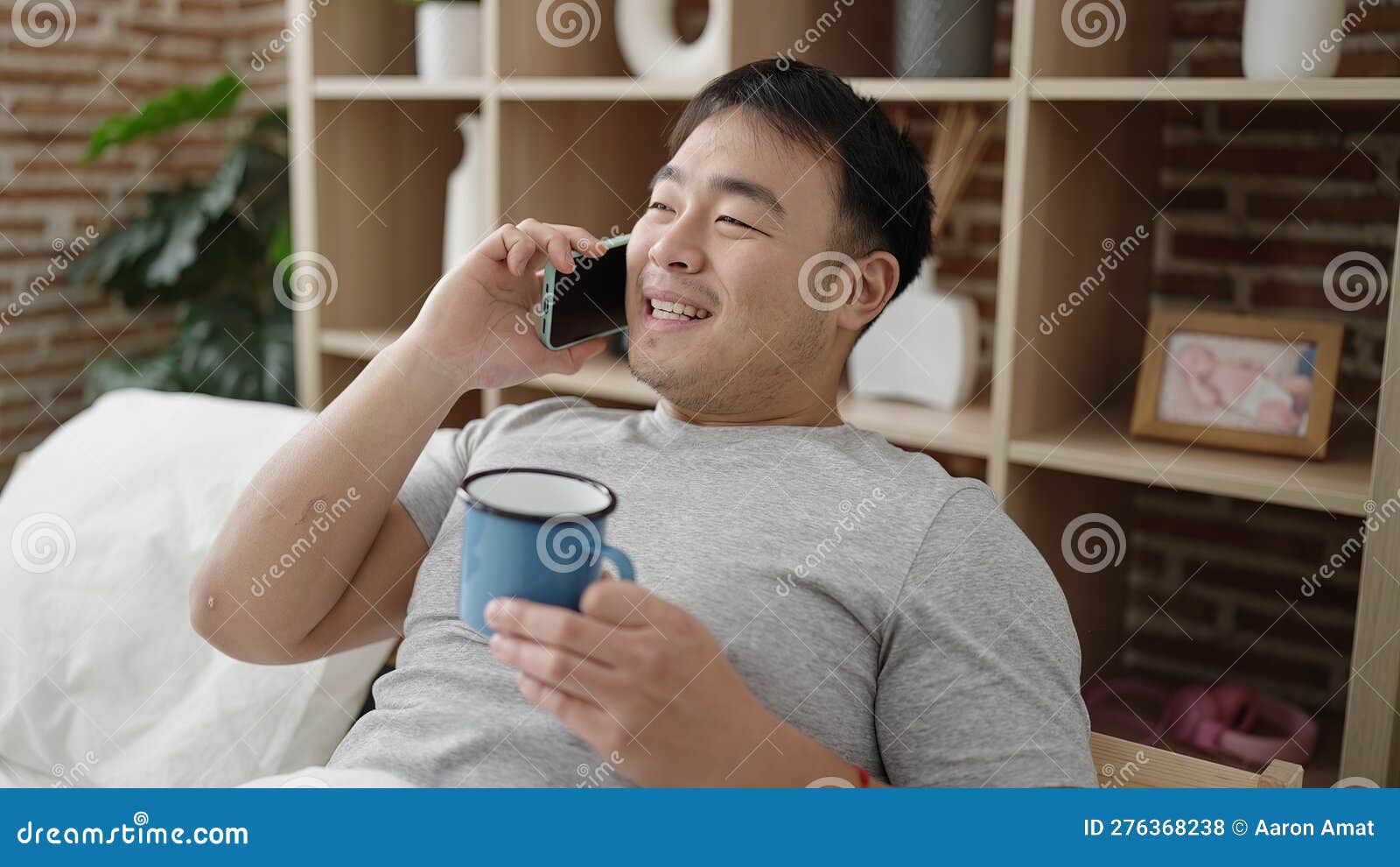 Young Chinese Man Talking on Smartphone Drinking Coffee at Bedroom ...