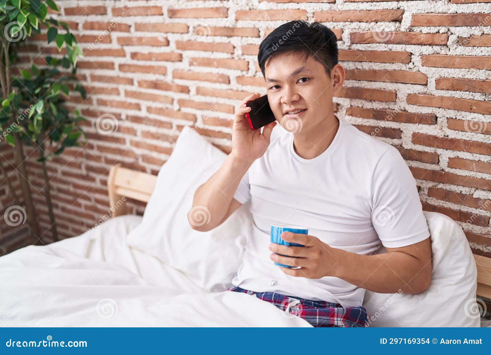 Young Chinese Man Talking on Smartphone Drinking Coffee at Bedroom ...