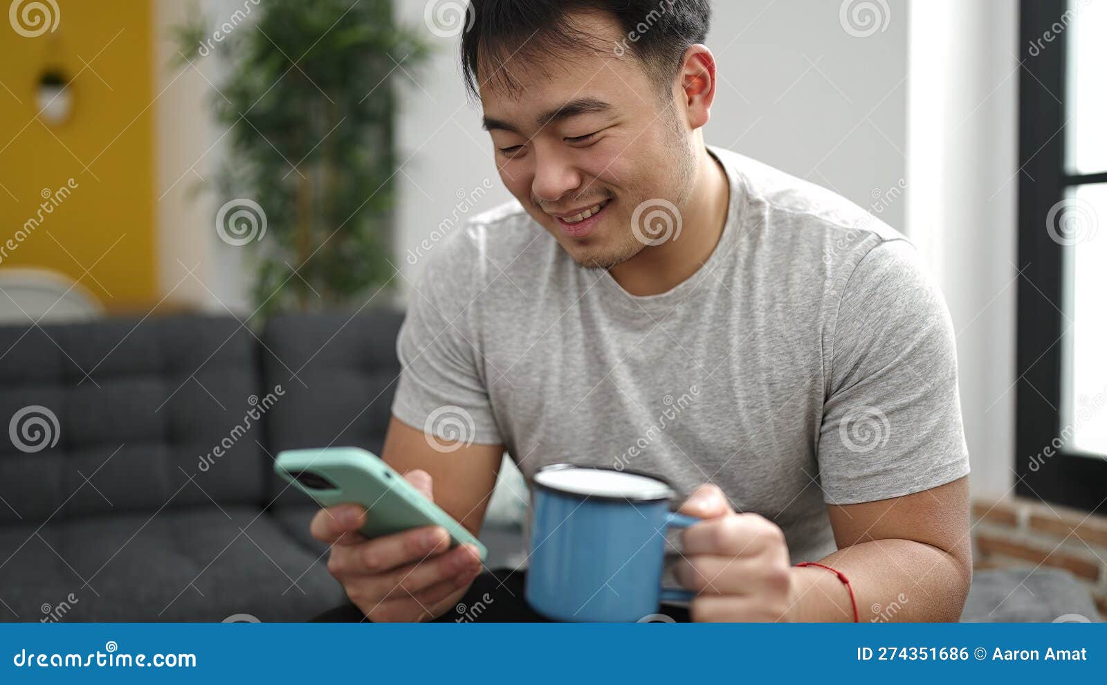 Young Chinese Man Using Smartphone Drinking Coffee at Home Stock Photo ...