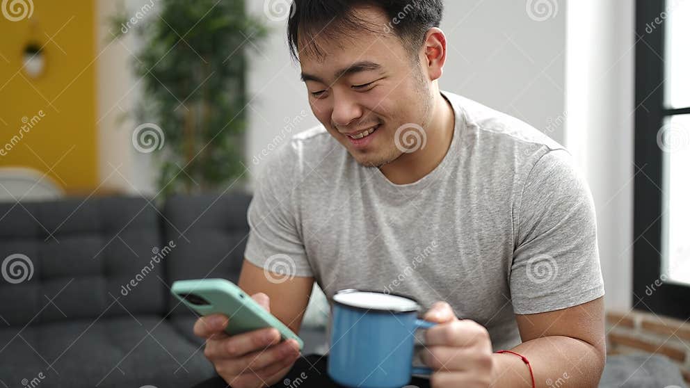 Young Chinese Man Using Smartphone Drinking Coffee at Home Stock Photo ...