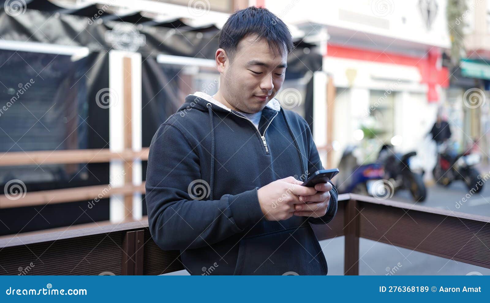 Young Chinese Man Using Smartphone with Relaxed Expression at Street ...