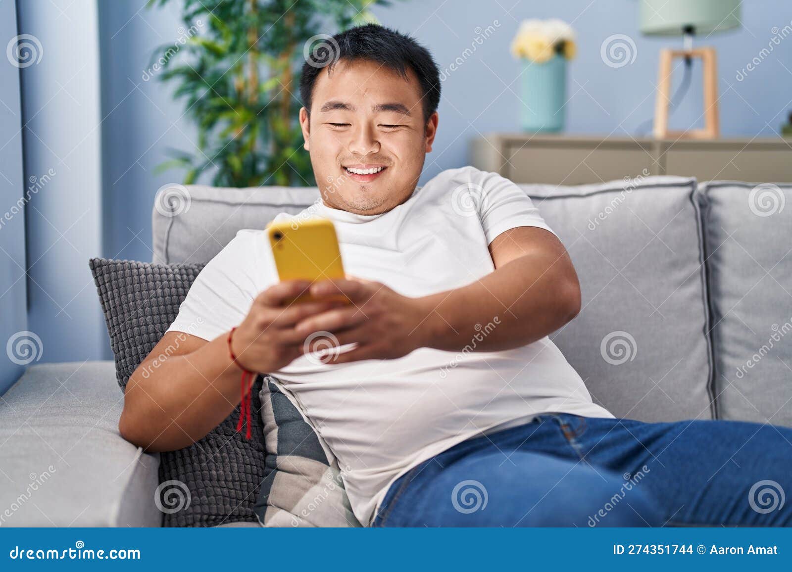 Young Chinese Man Using Smartphone Sitting on Sofa at Home Stock Photo ...