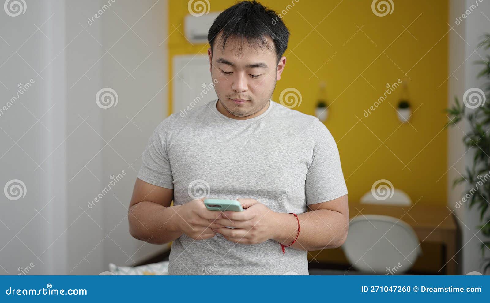 Young Chinese Man Using Smartphone Standing at Home Stock Photo - Image ...
