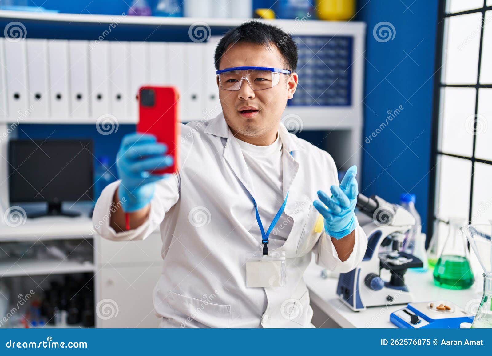 Young Chinese Man Wearing Scientist Uniform Having Video Call at ... Young Chinese Man Wearing Scientist Uniform Having Video Call at ...