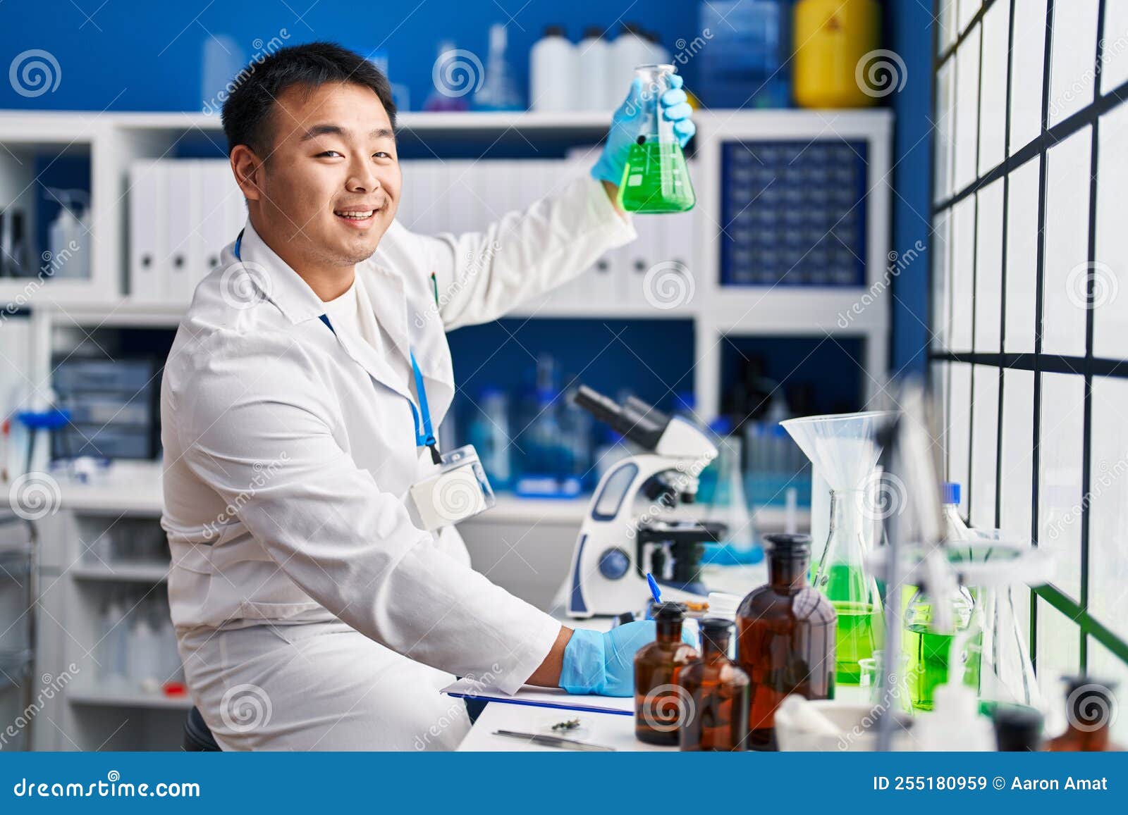 Young Chinese Man Wearing Scientist Uniform Measuring Liquid at ...