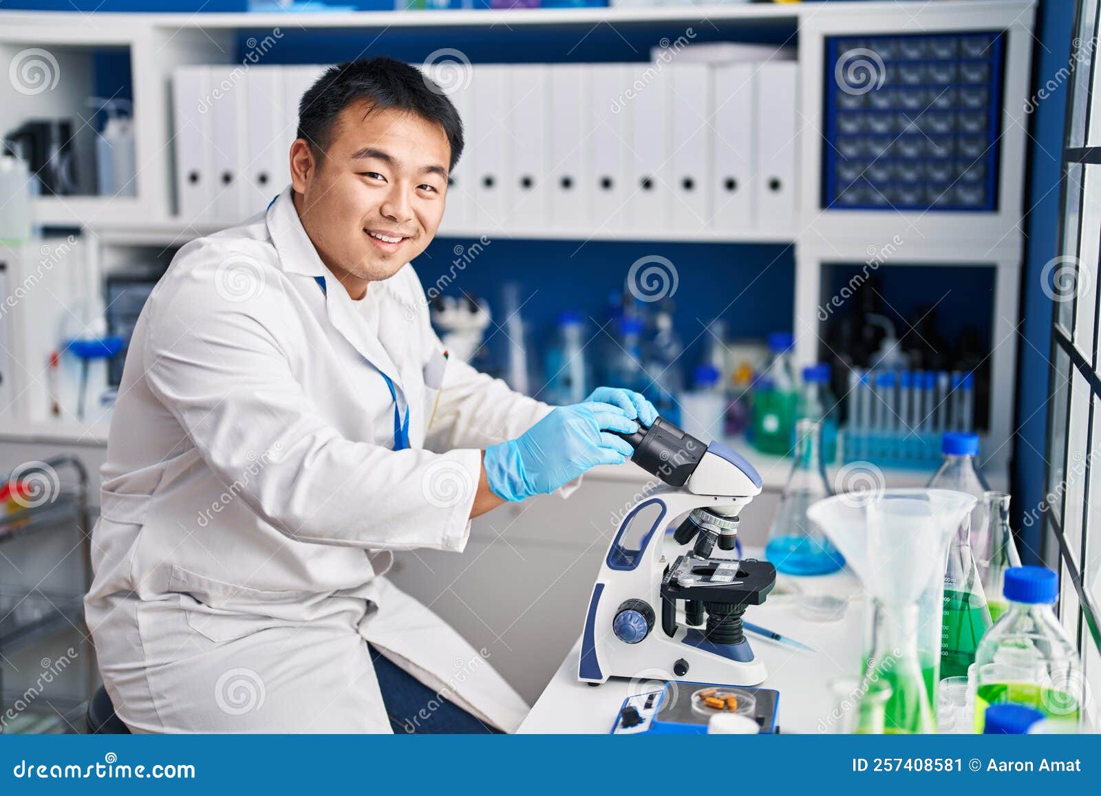 Young Chinese Man Wearing Scientist Uniform Using Microscope at ... Young Chinese Man Wearing Scientist Uniform Using Microscope at ...
