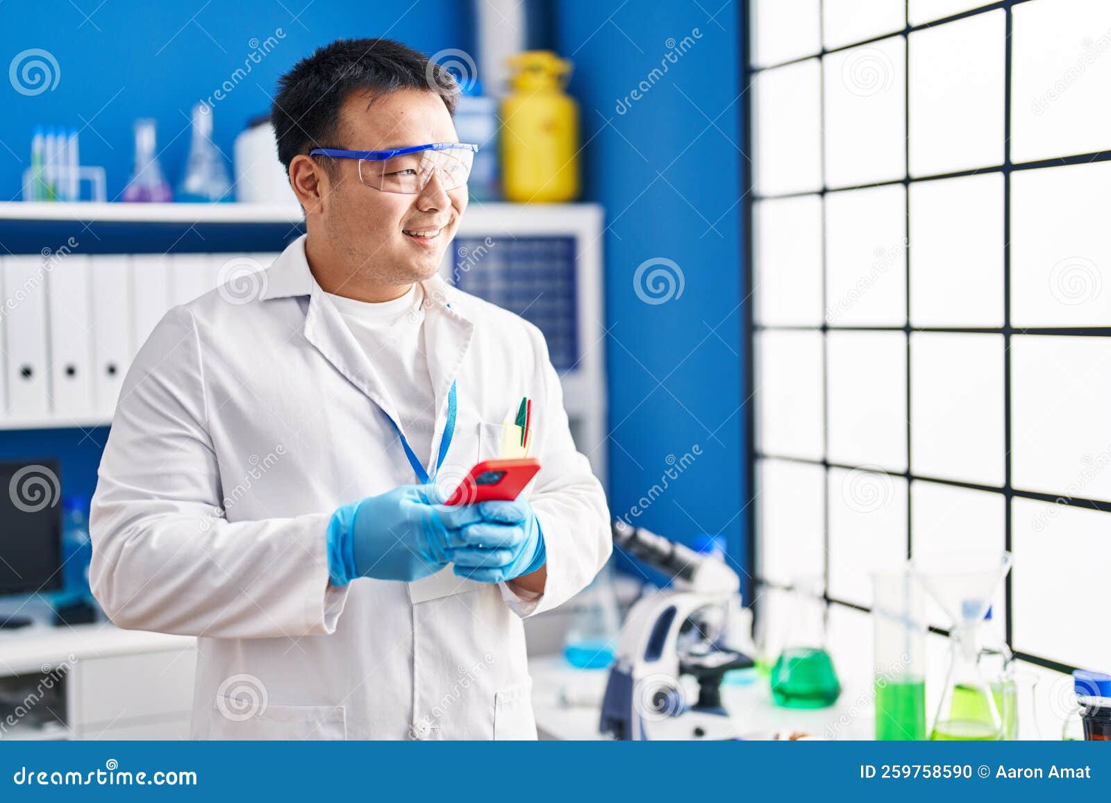 Young Chinese Man Wearing Scientist Uniform Using Smartphone at ...