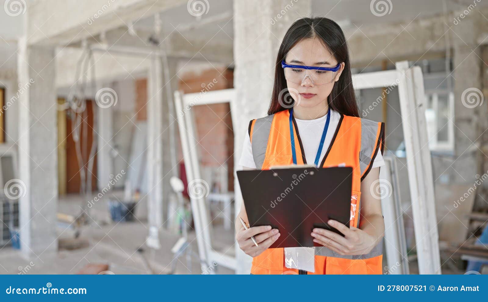 Young Chinese Woman Builder Reading Document at Construction Site Stock ...