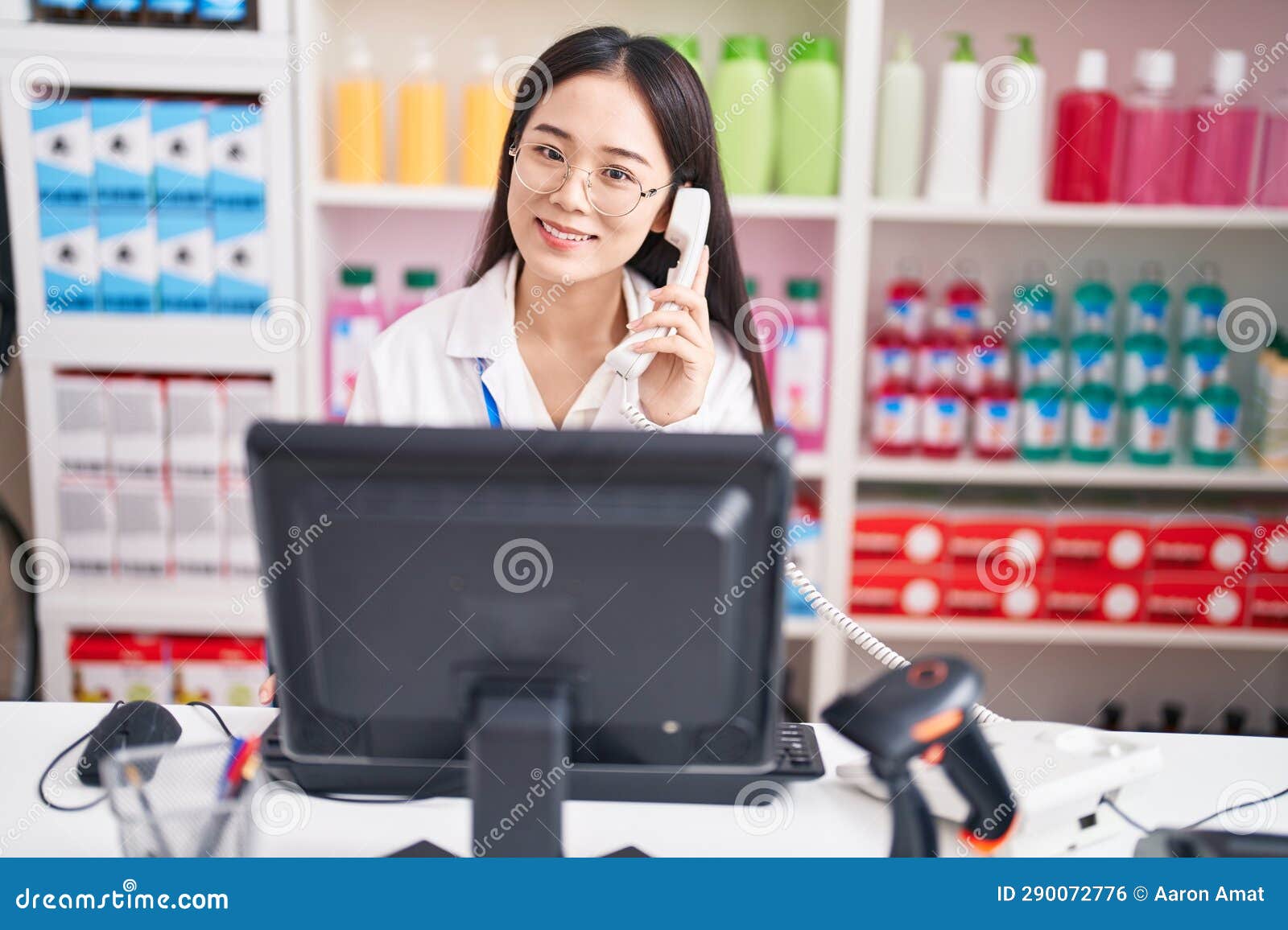 Young Chinese Woman Pharmacist Talking on Telephone Using Computer at ...