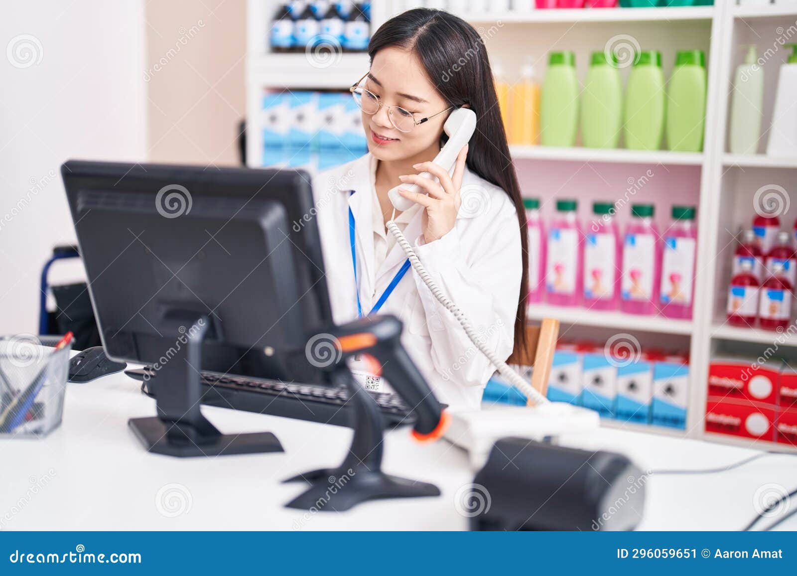 Young Chinese Woman Pharmacist Talking on Telephone Using Computer at ...