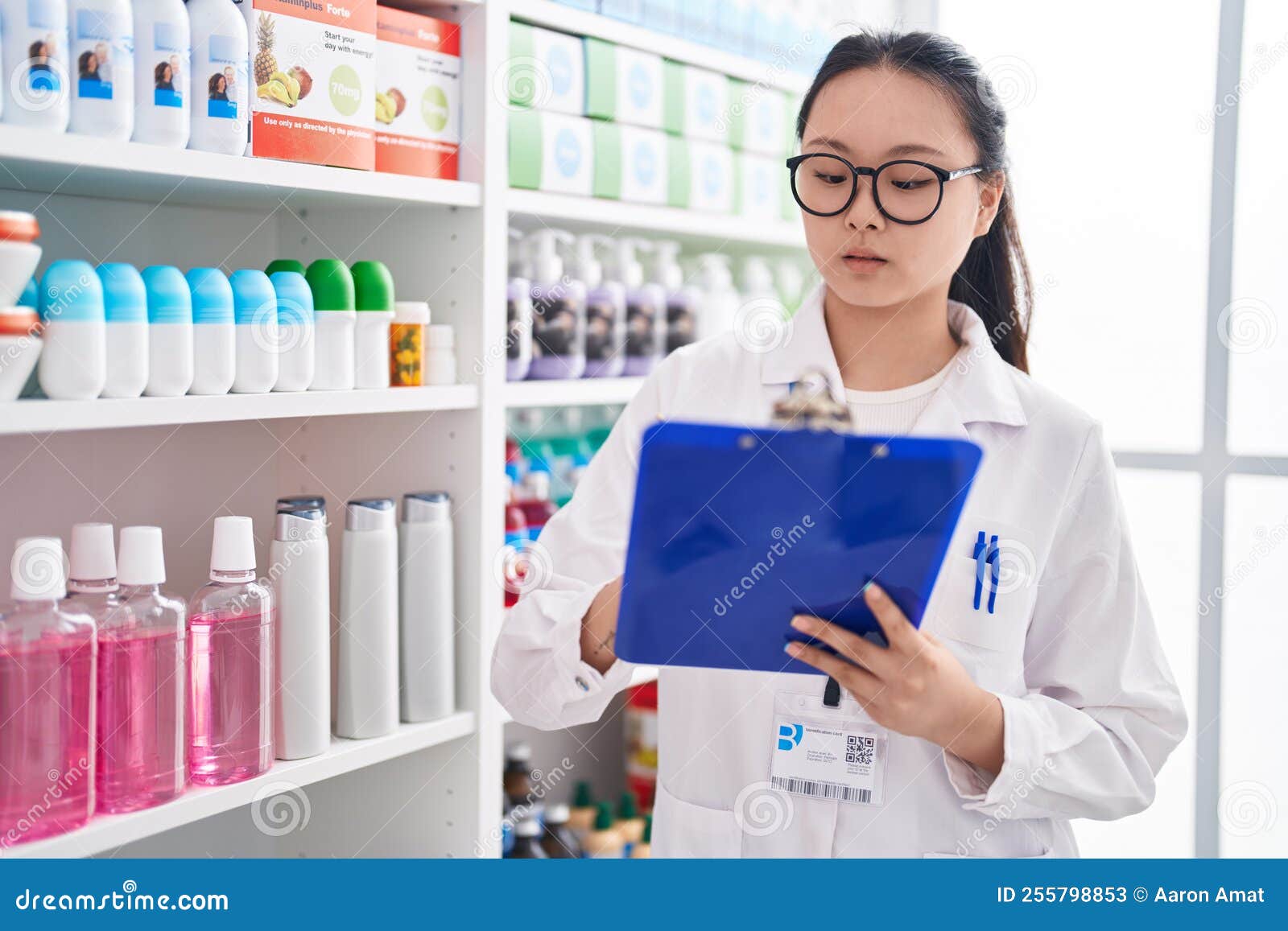 Young Chinese Woman Pharmacist Writing on Document at Pharmacy Stock ...