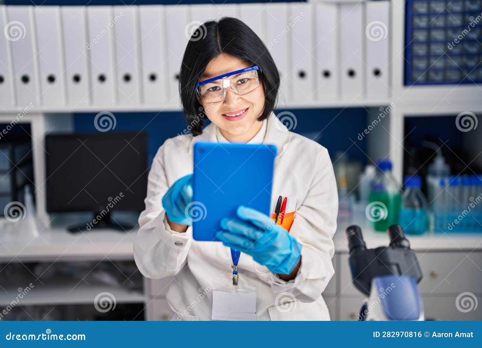 Young Chinese Woman Scientist Using Touchpad Working at Laboratory ...