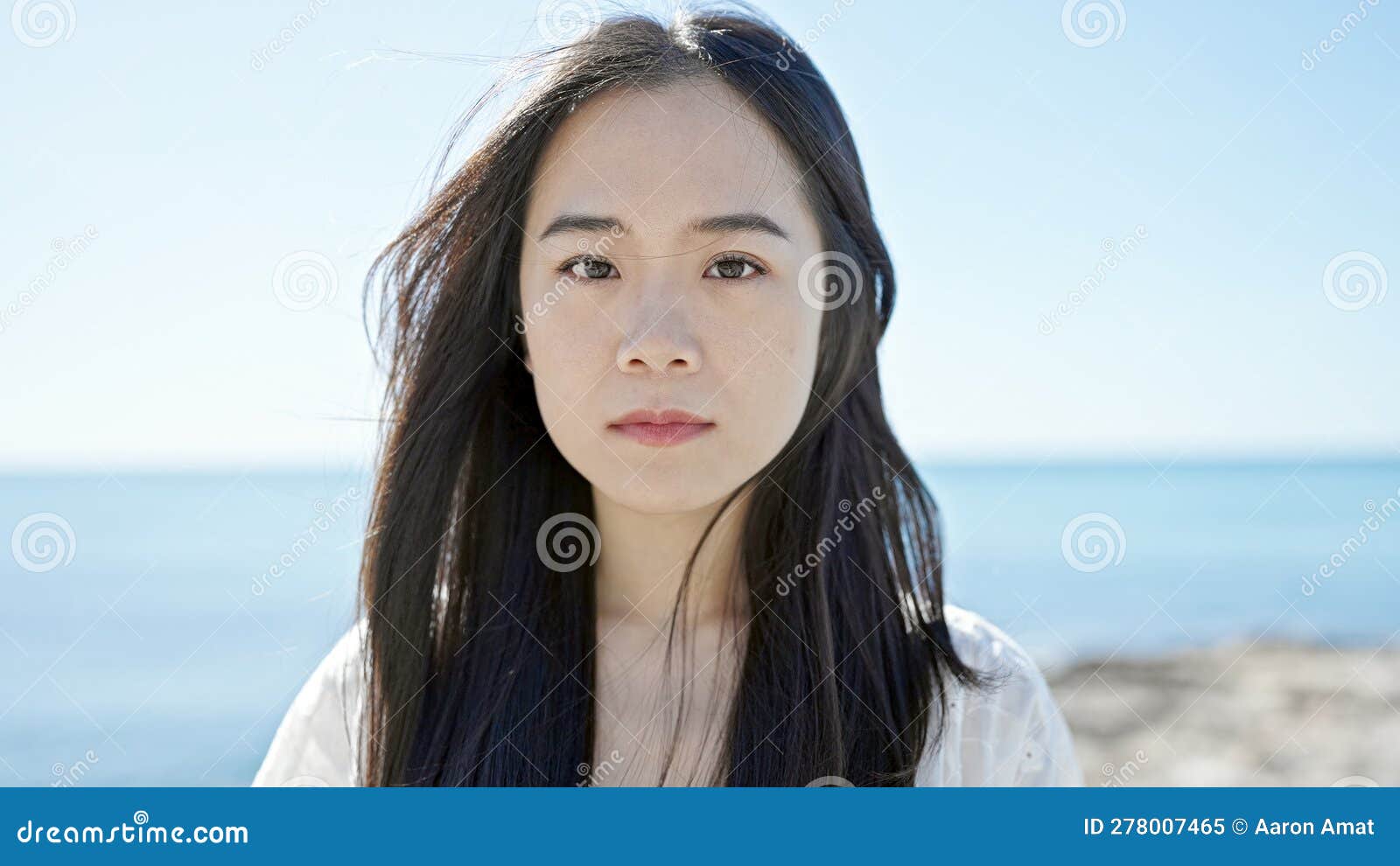 Young Chinese Woman Standing with Serious Expression at Seaside Stock ...