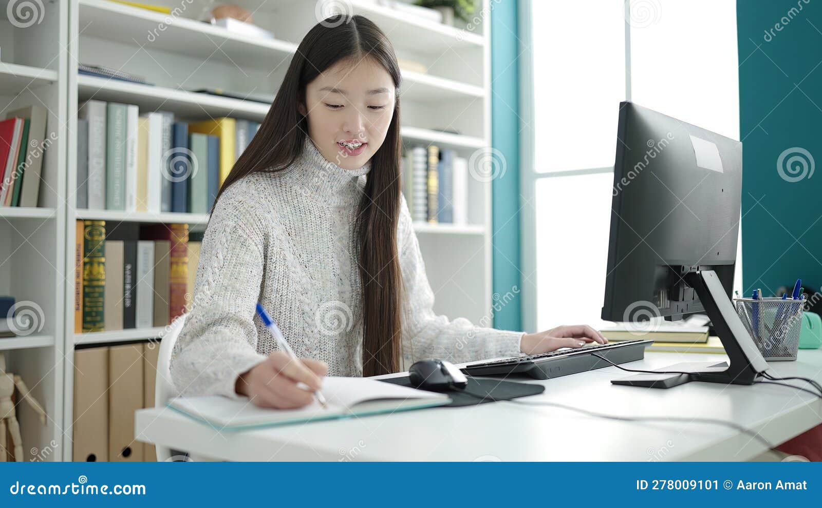 Young Chinese Woman Student Using Computer Writing on Notebook at ...