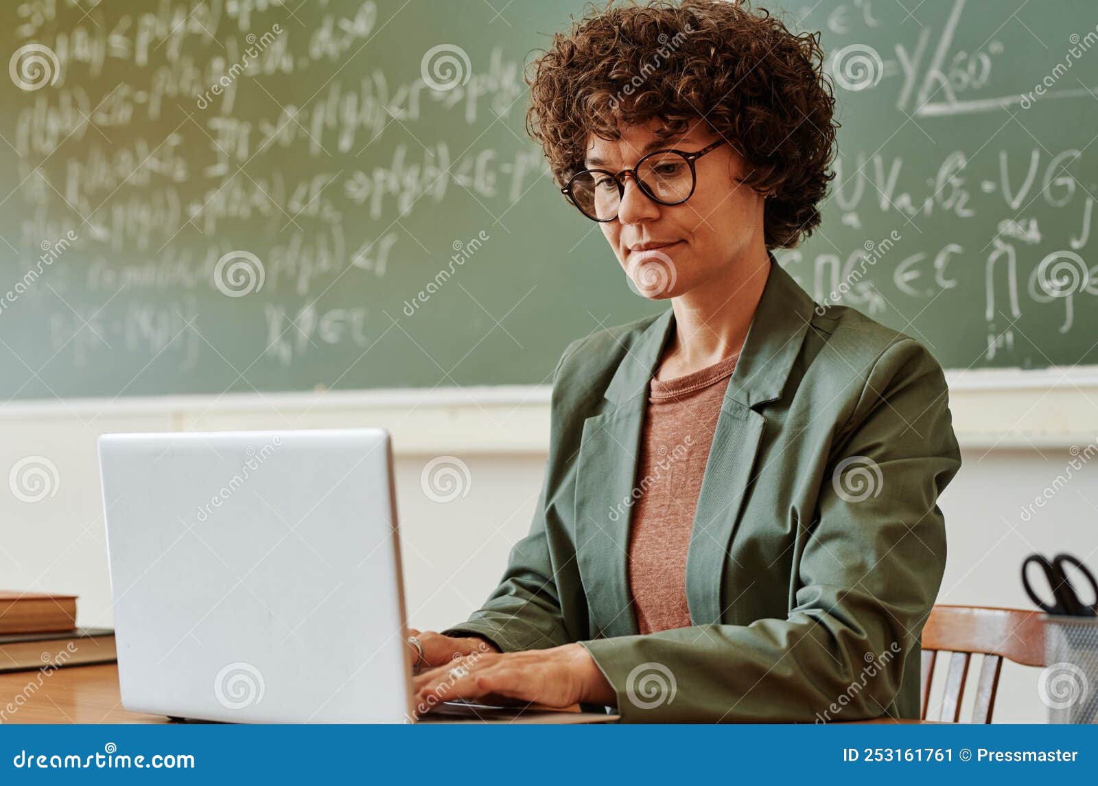 Young Confident Teacher Typing on Laptop Keypad while Sitting by ...
