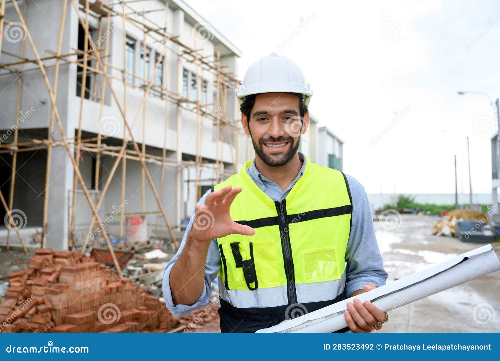 Young Constructor Engineer Man Smiling Holding Blueprint while Talking about Building ...
