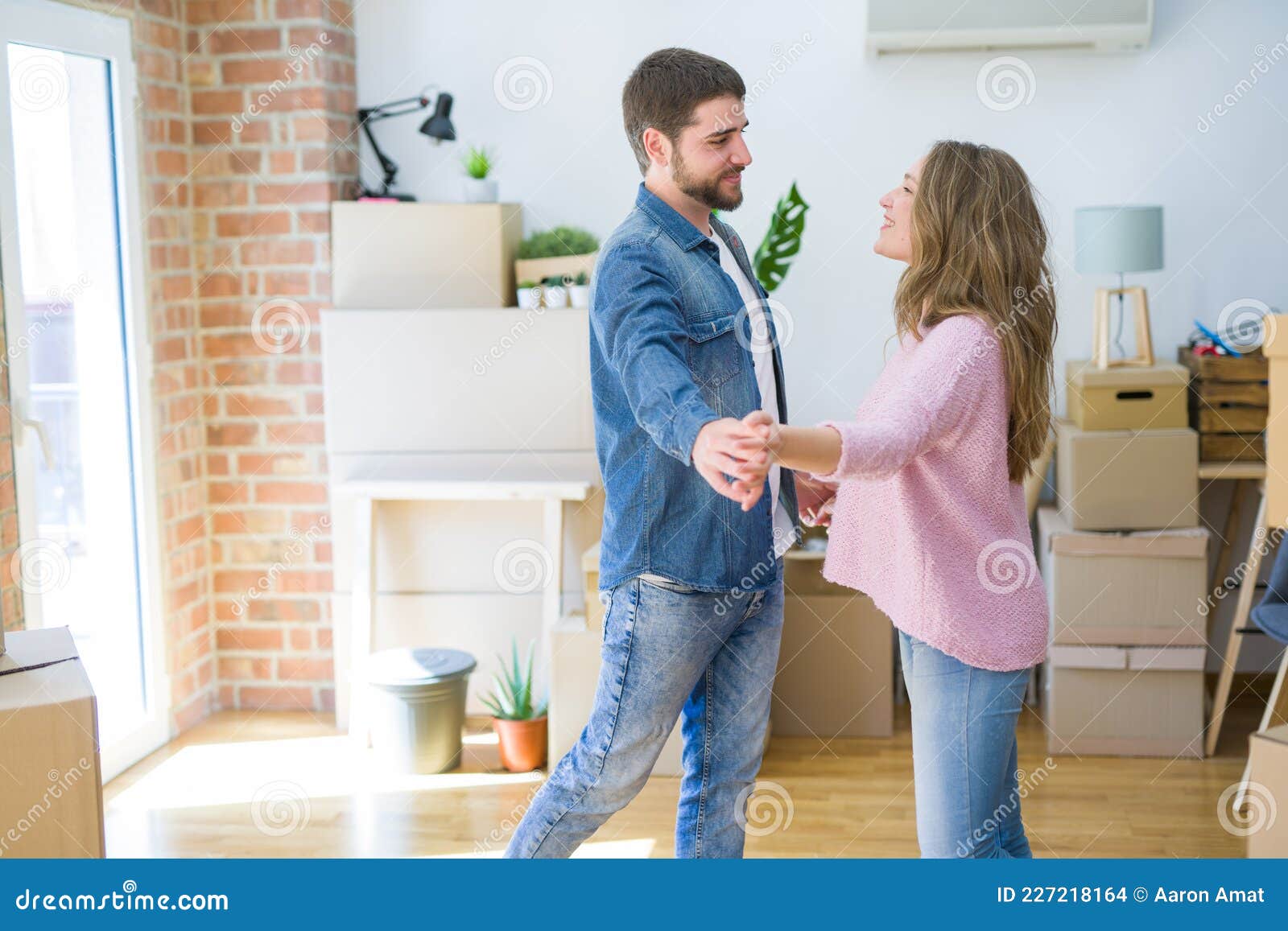Young Couple Dancing Celebrating Moving To New Apartment Around