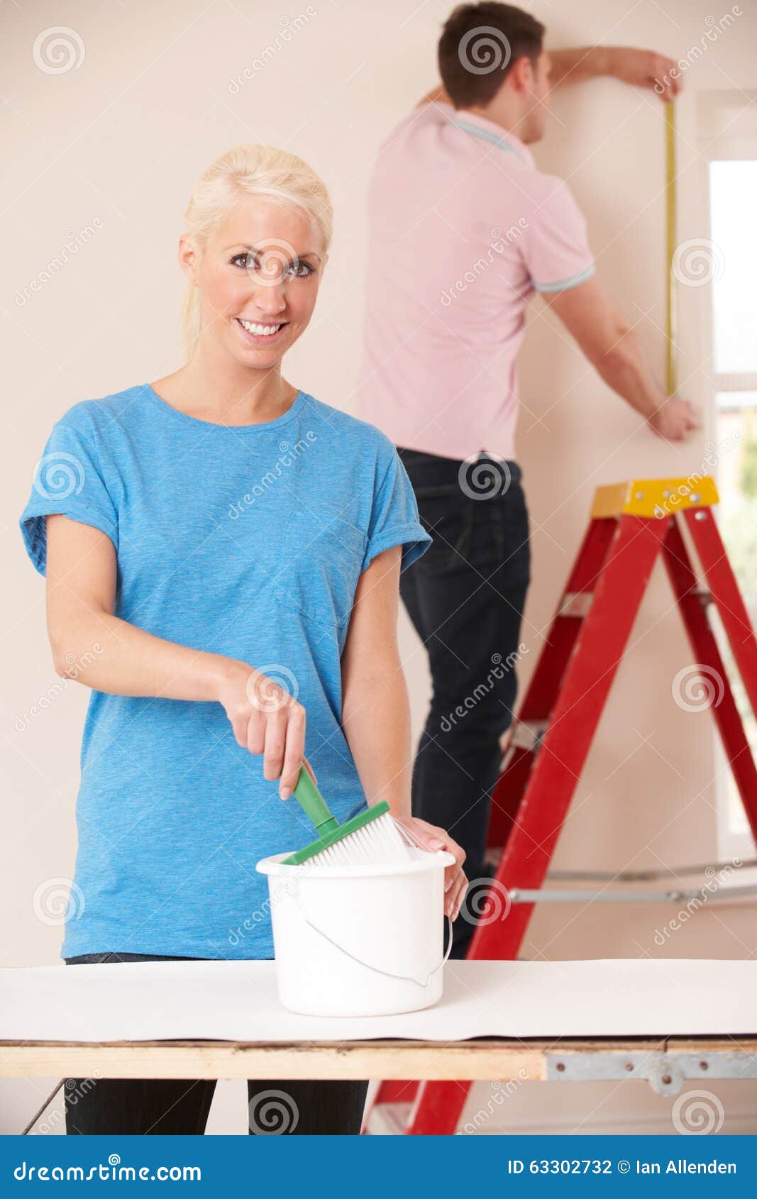 Young Couple Decorating Home Together Stock Photo - Image of wallpaper ...