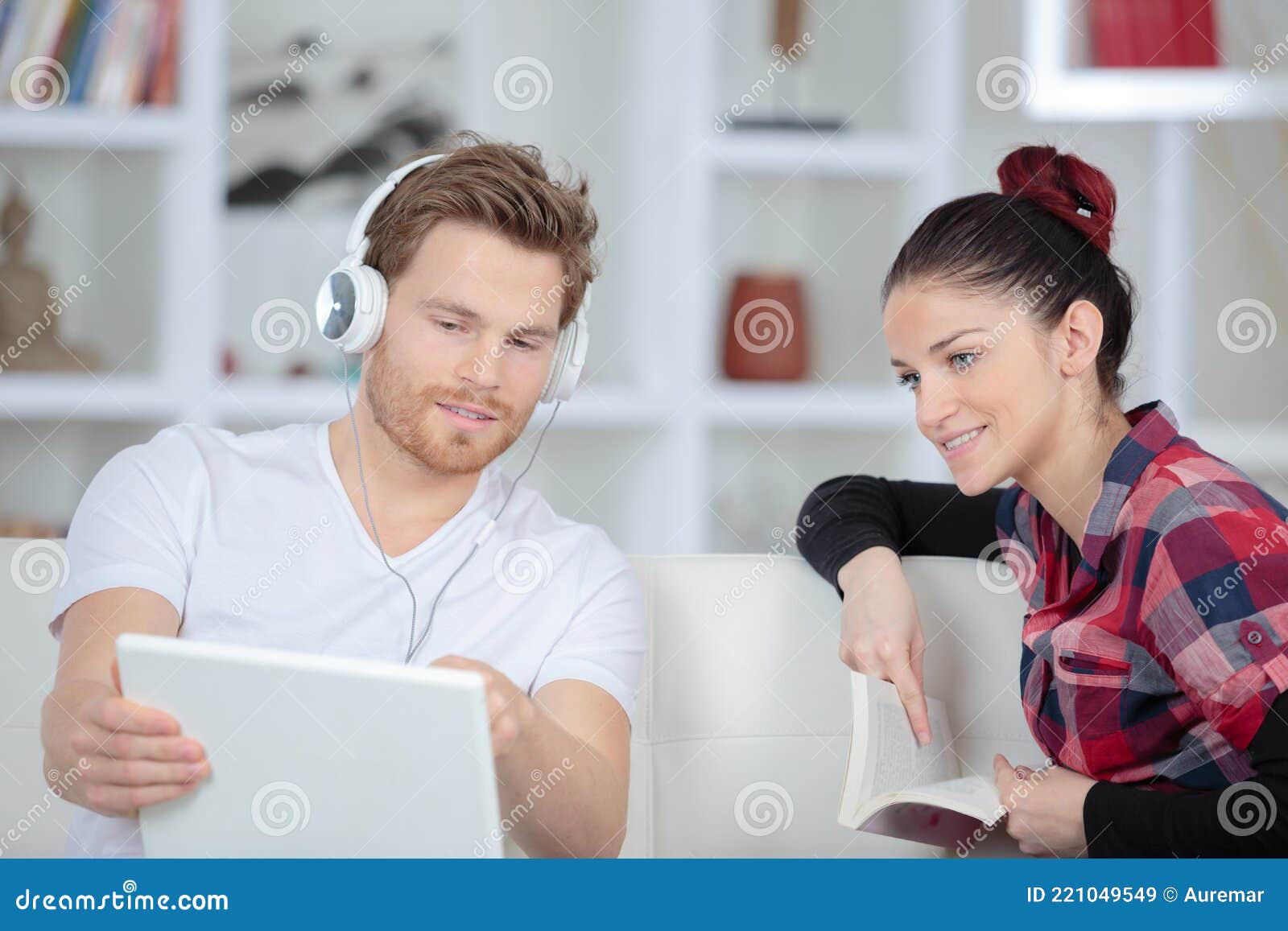 Young Couple Entertaining Themselves with Book and Laptop Stock Image ...
